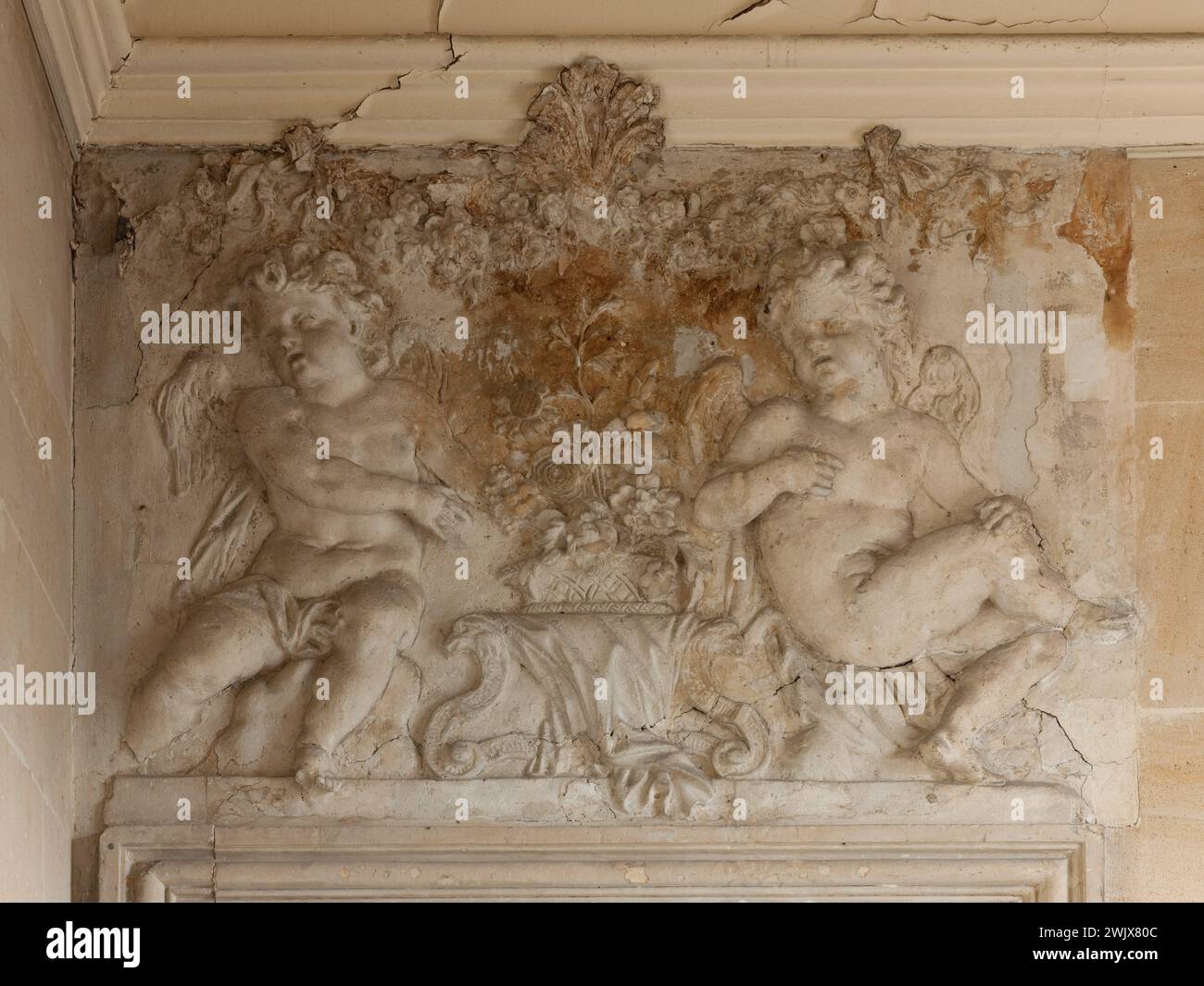 Two putti seated framing a bouquet of flowers. Plaster bas-relief. Paris, Carnavalet museum ...