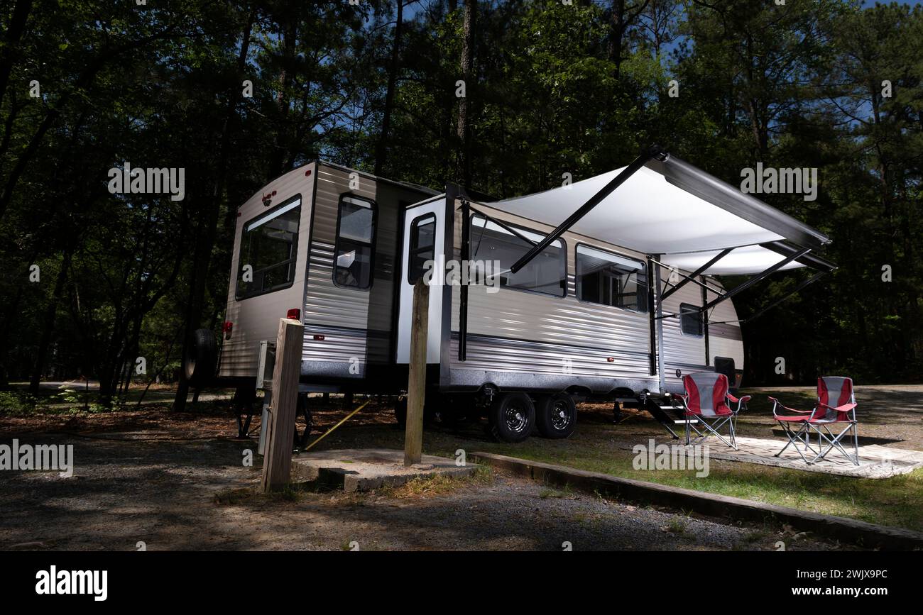 Red outdoor chairs undeer the awnings of a campter trailer in a ...