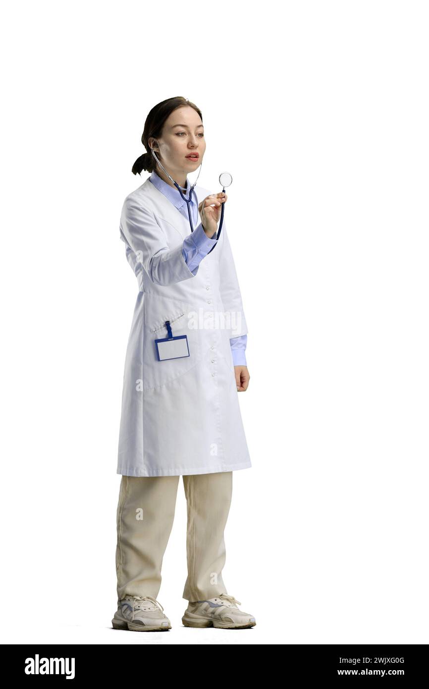 A female doctor, full-length, on a white background, uses a stethoscope ...