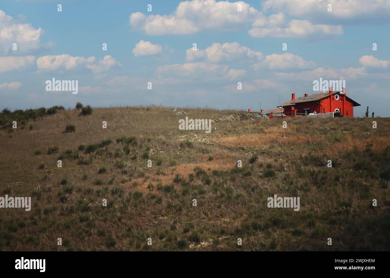Vast natural landscape under cloudy sky, with red house in distance ...