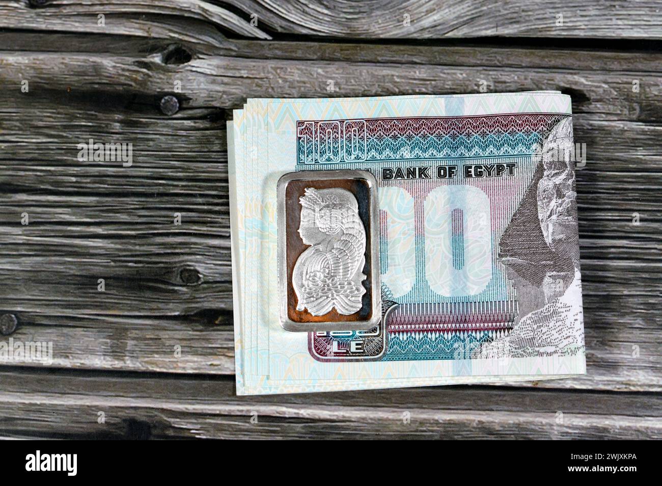 Folded Egyptian 100 EGP pounds cash money and silver precious metal ...