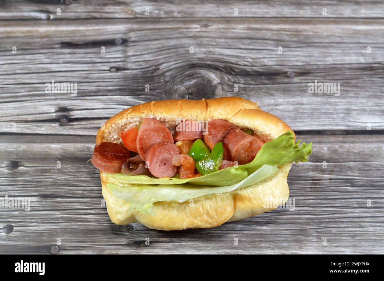 Partially sliced hotdog bun with slices of hot dog grilled beef sausage ...