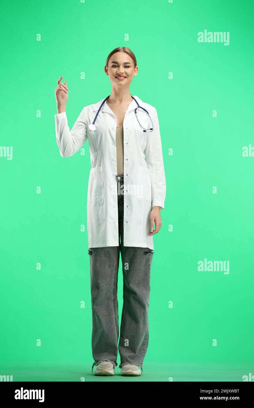 A female doctor, full-length, on a green background, points up Stock ...