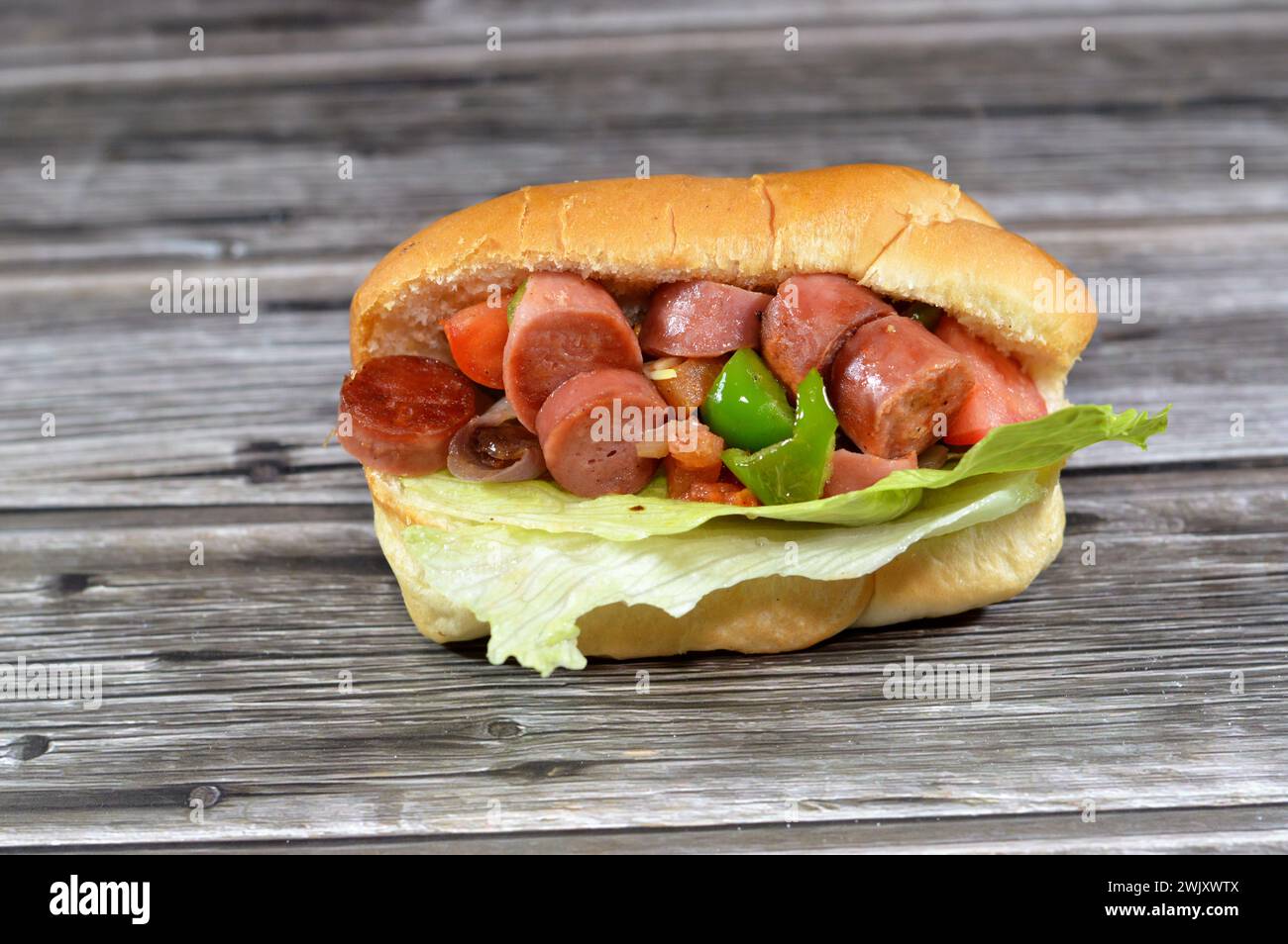 Partially sliced hotdog bun with slices of hot dog grilled beef sausage ...