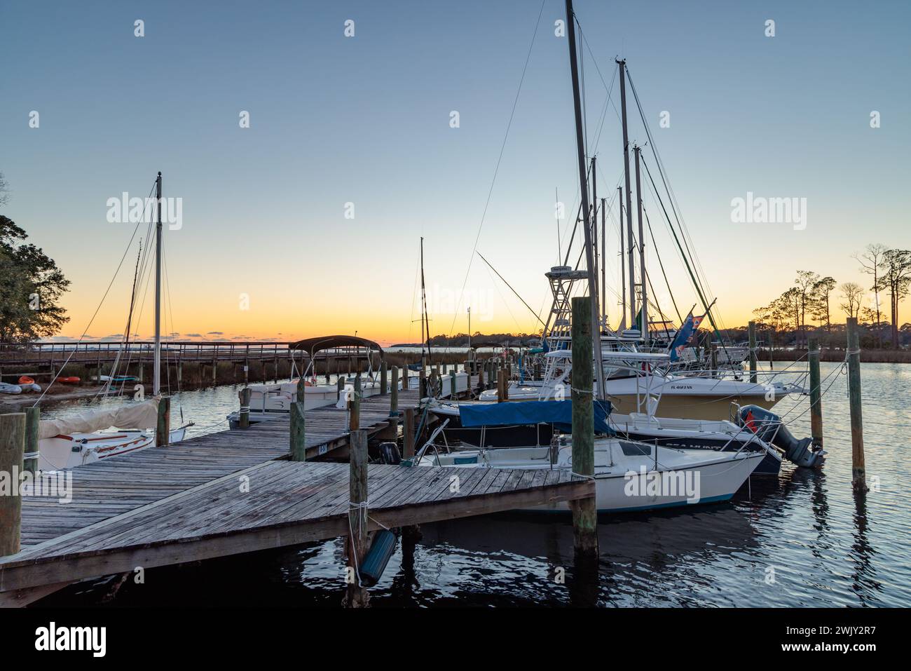 Sun setting behind fishing boats and sailboats in marina on Ward Cove ...