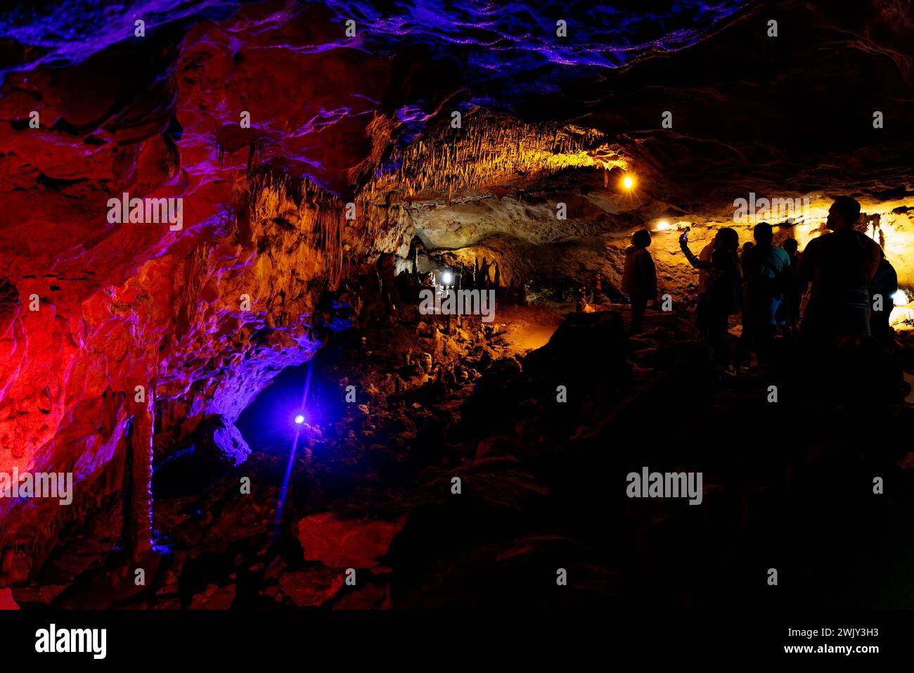 Tourists walking past limestone rock formations in a cave at Florida ...
