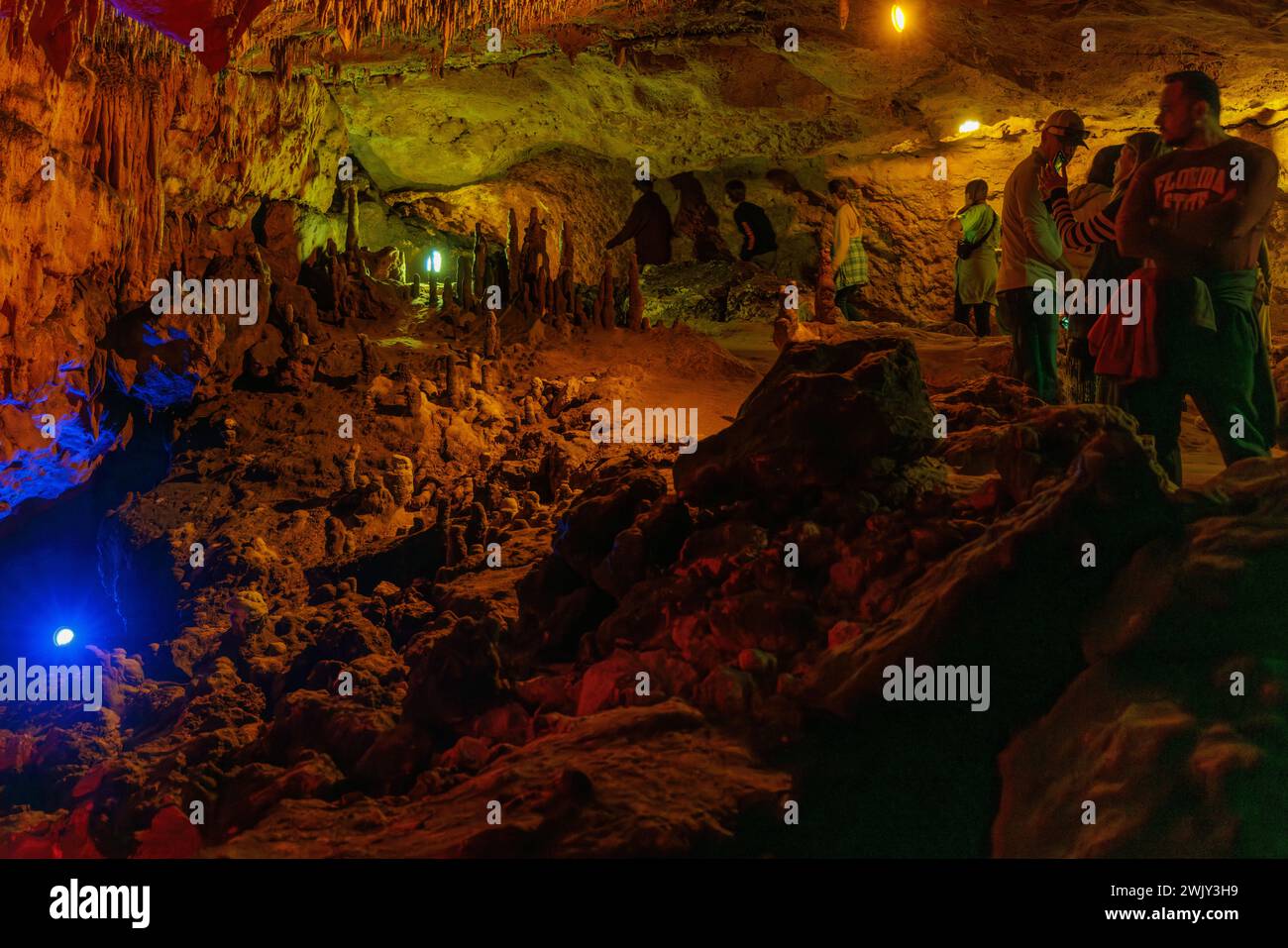 Tourists walking past limestone rock formations in a cave at Florida ...