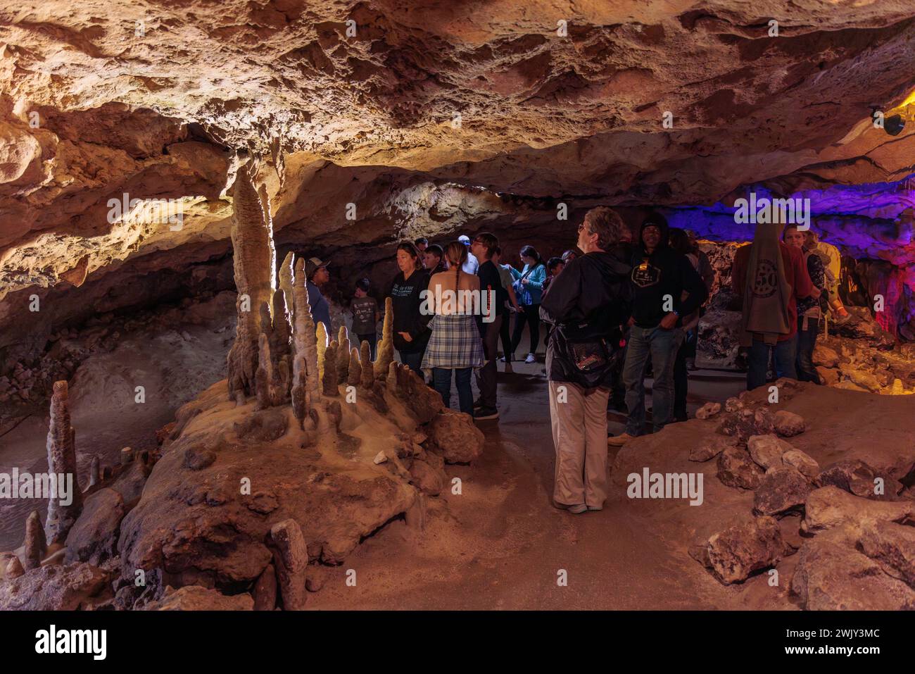 Tourists walking past limestone rock formations in a cave at Florida ...