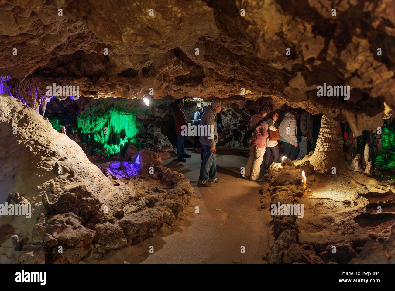 Tourists walking past limestone rock formations in a cave at Florida ...