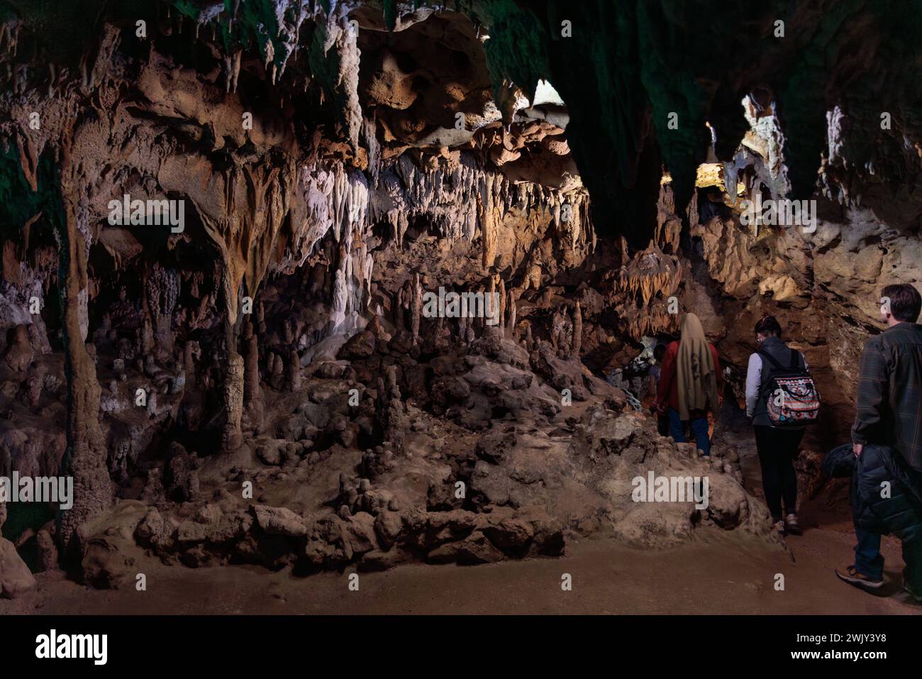 Tourists walking past limestone rock formations in a cave at Florida ...