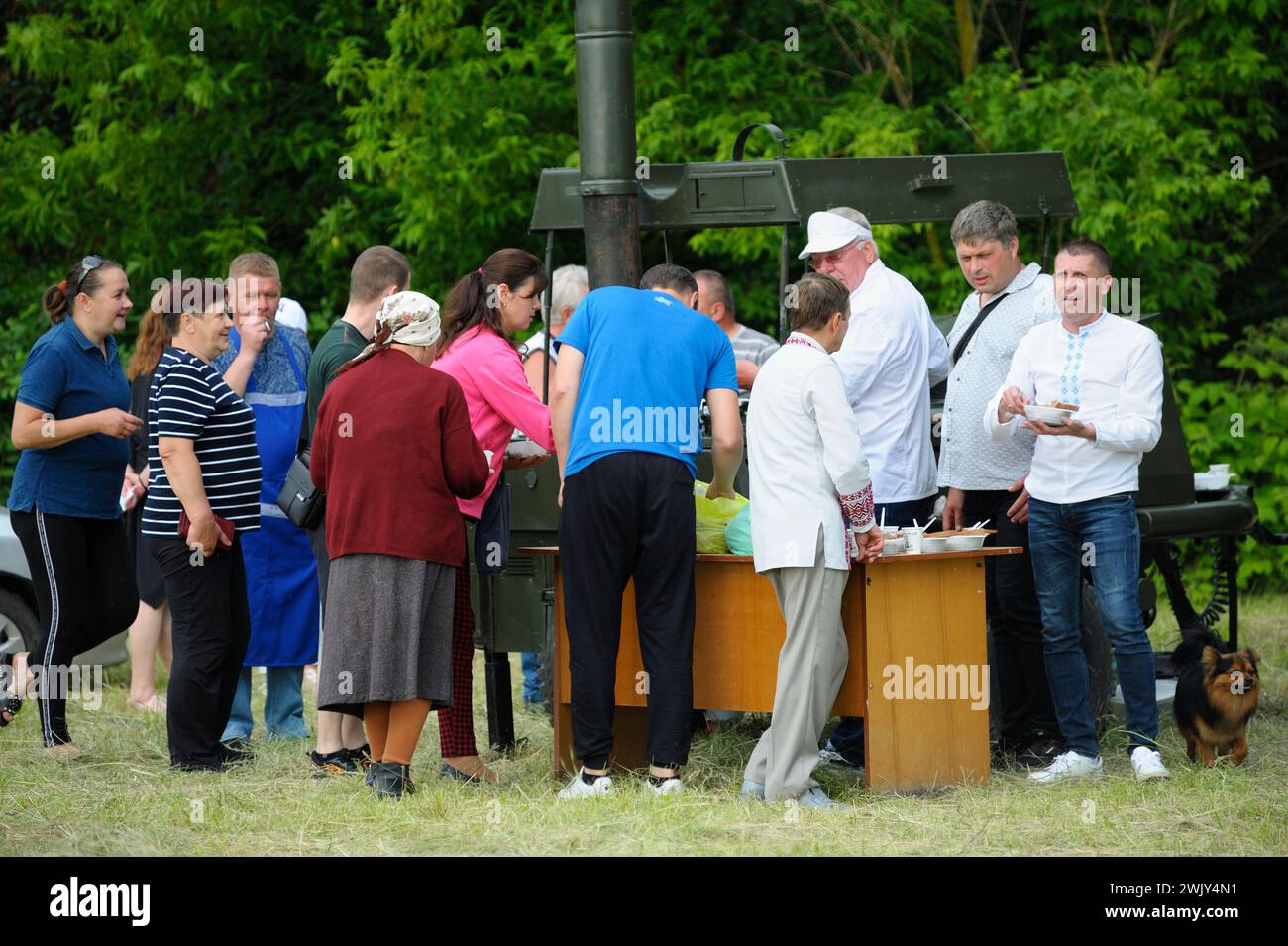 Cook standing in front of mobile field kitchen and putting free meal in ...