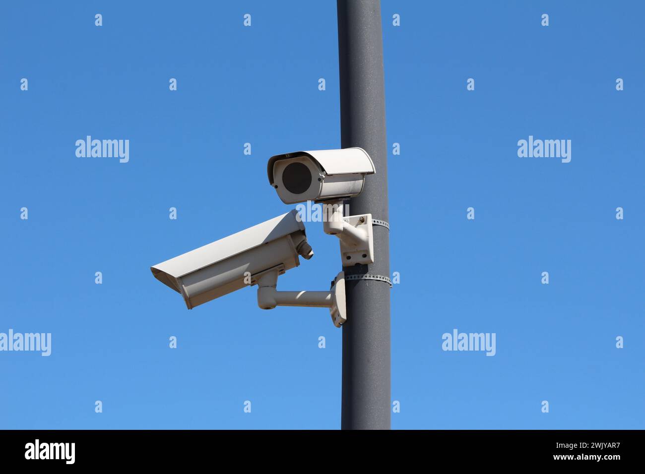 Two small fake dummy modern white closed circuit TV CCTV security cameras looking in opposite ...