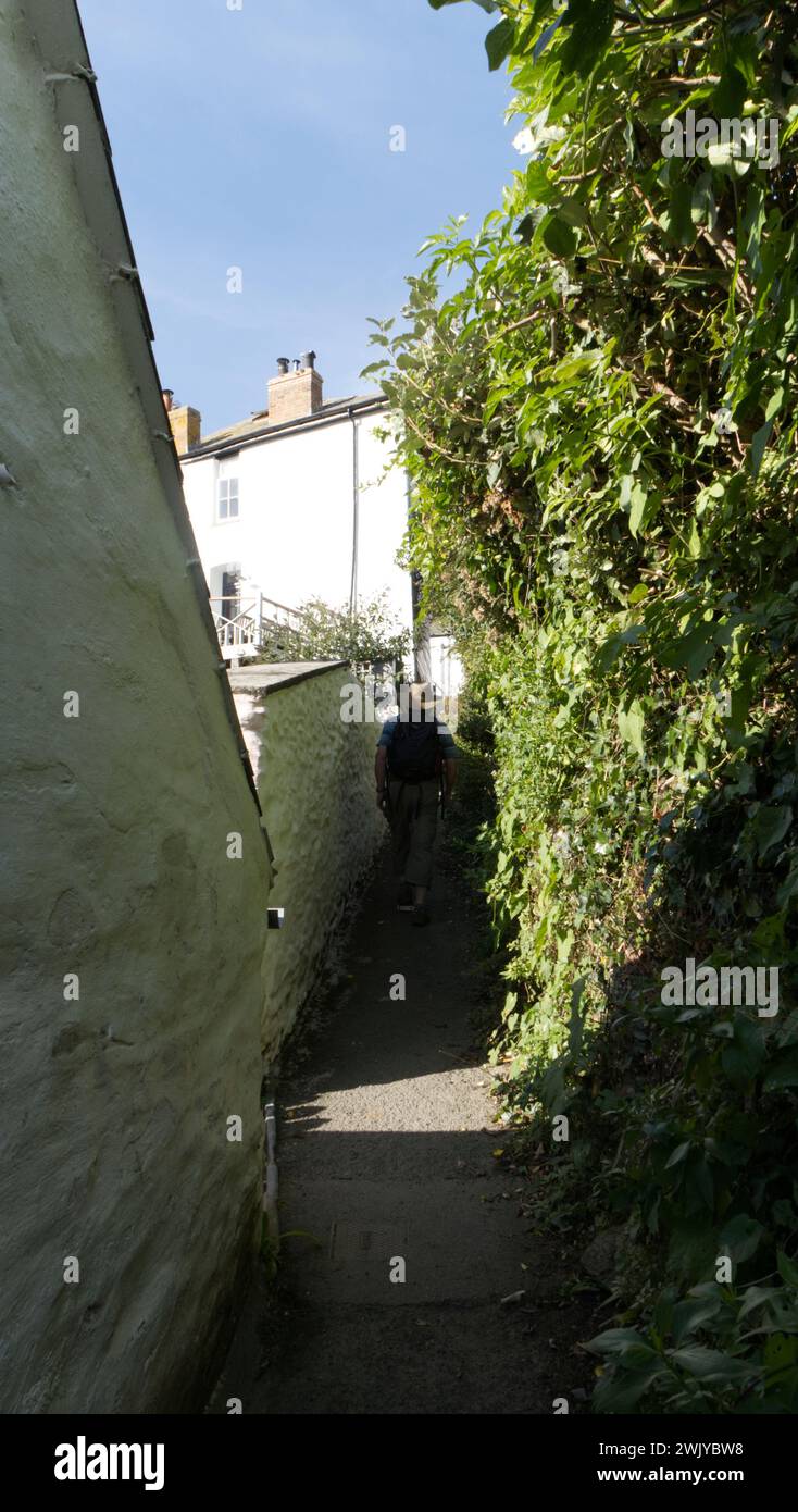 Man walking up a narrow path between houses in Port Isaac, Cornwall, UK ...