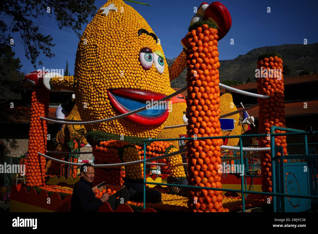 A worker places citrus fruits on an olympic boxing carnival float ...