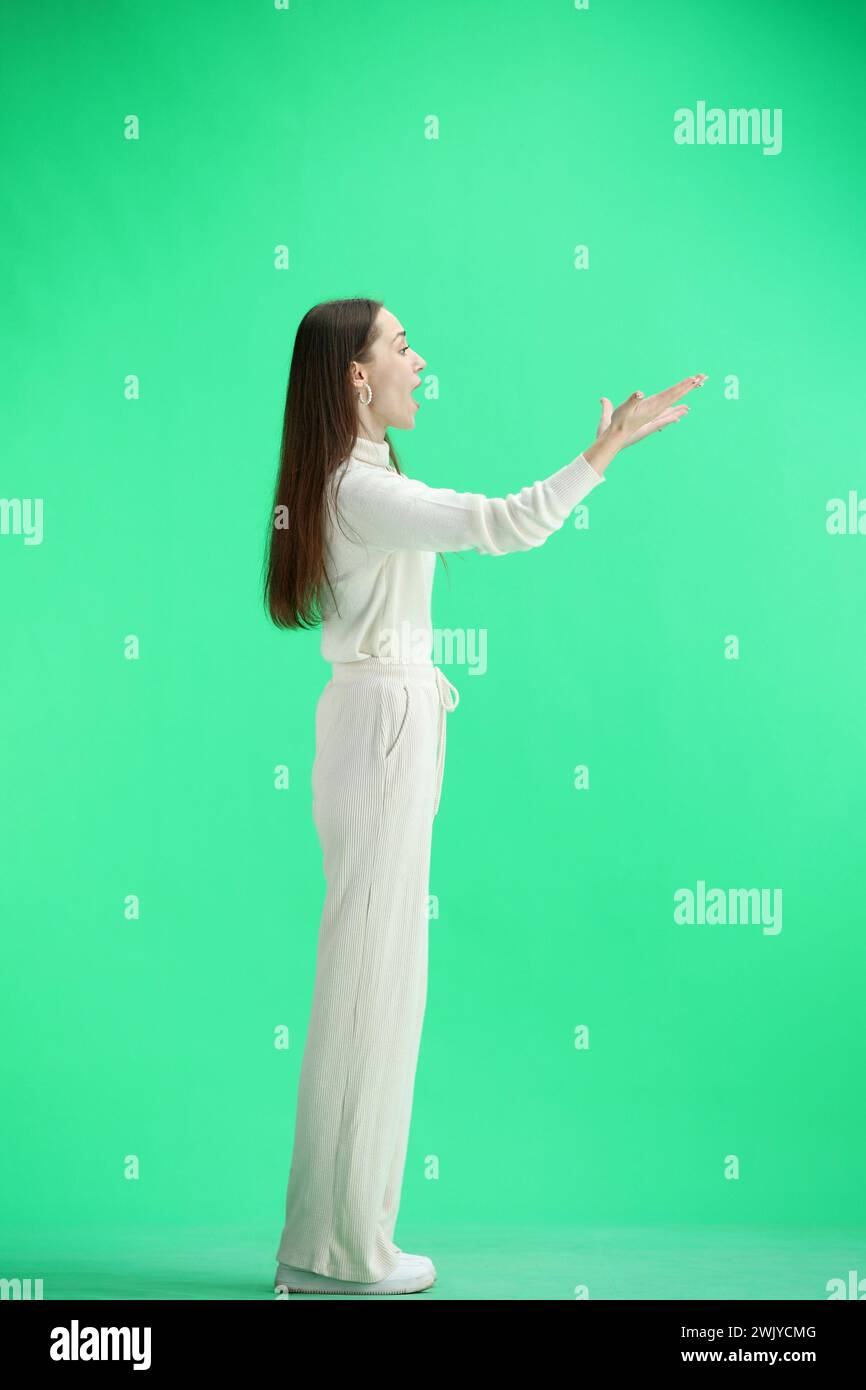 A woman, full-length, on a green background, raised her hands up Stock ...