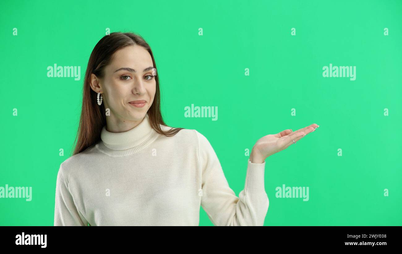 A woman, close-up, on a green background, points to the side Stock ...