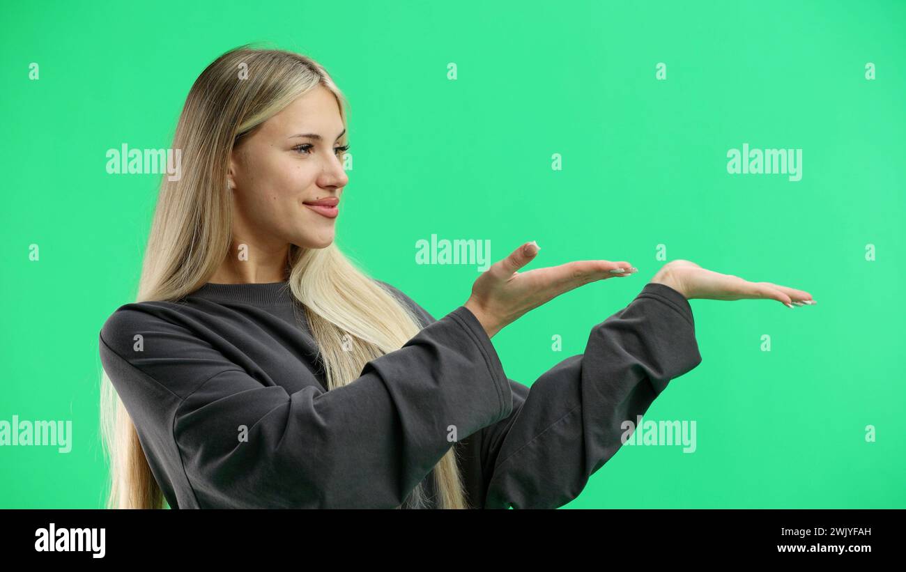A woman, close-up, on a green background, points to the side Stock ...