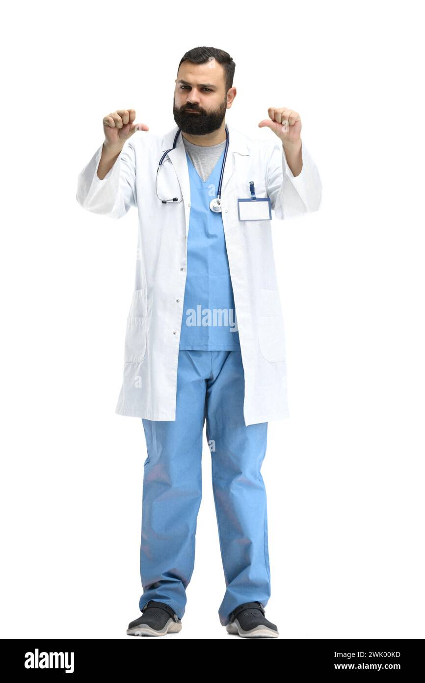 A male doctor, full-length, on a white background, shows his thumbs ...