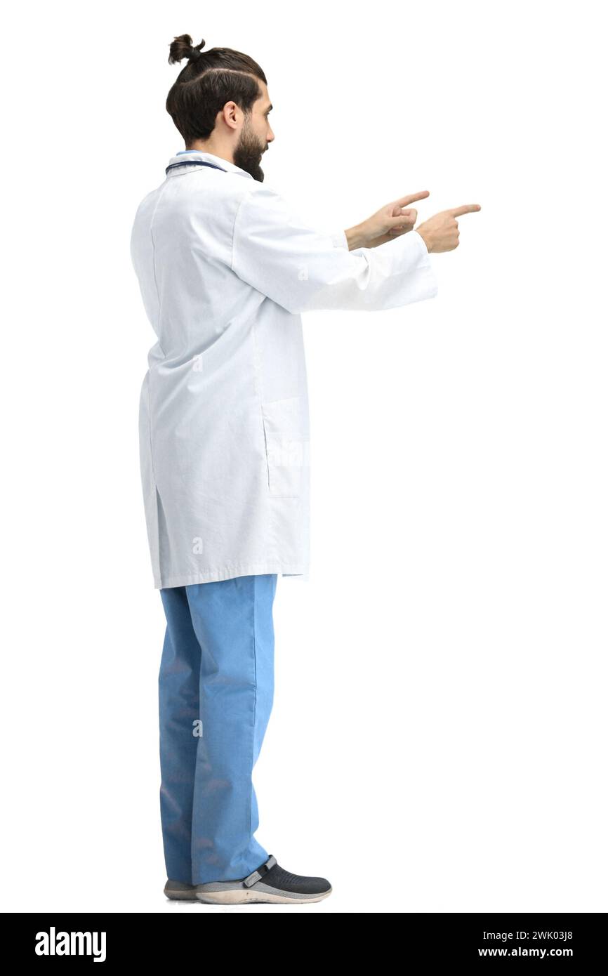 The male doctor, full-length, on a white background, points to the side ...