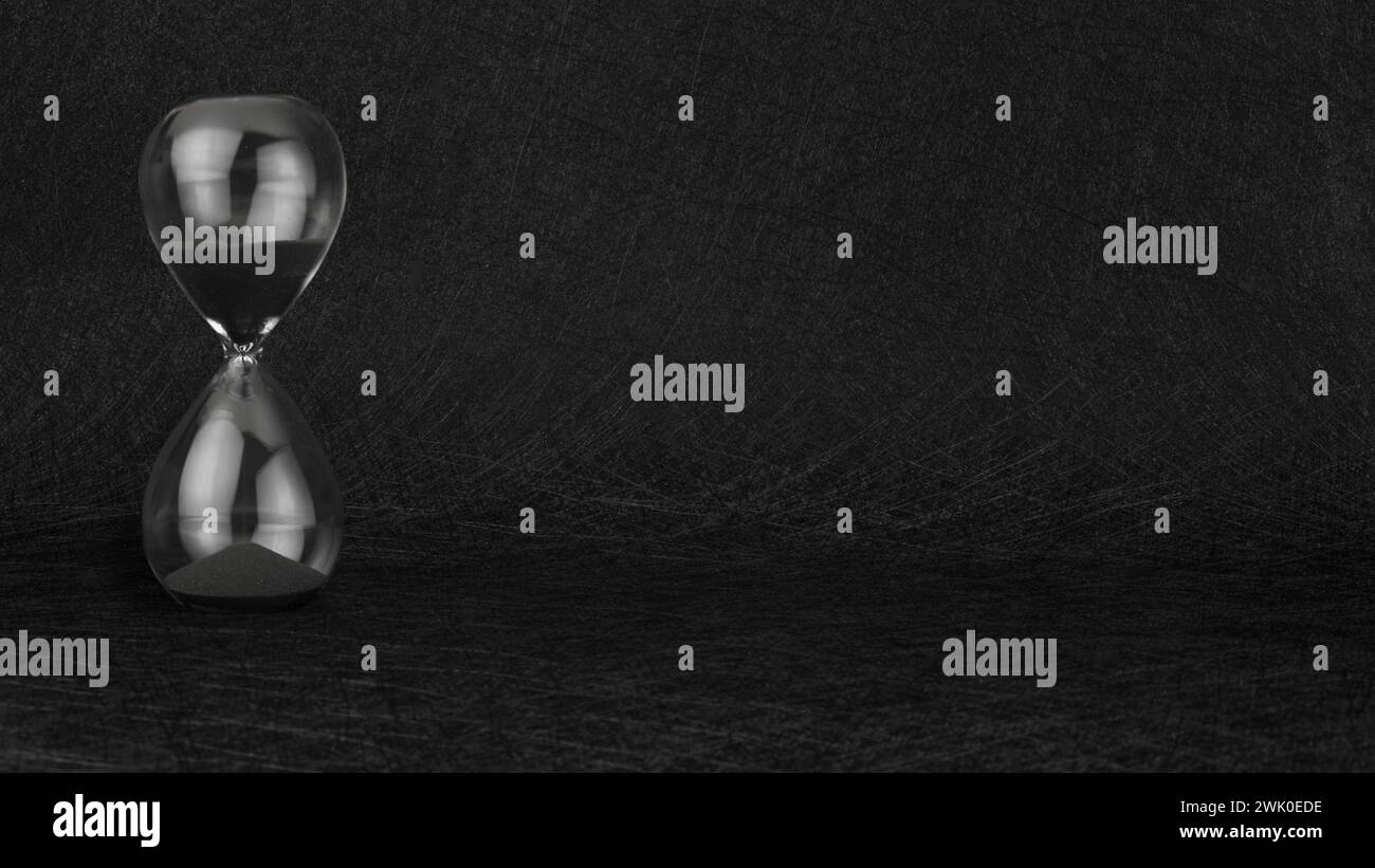 Black sand clock timer hourglass on black textured background Stock ...