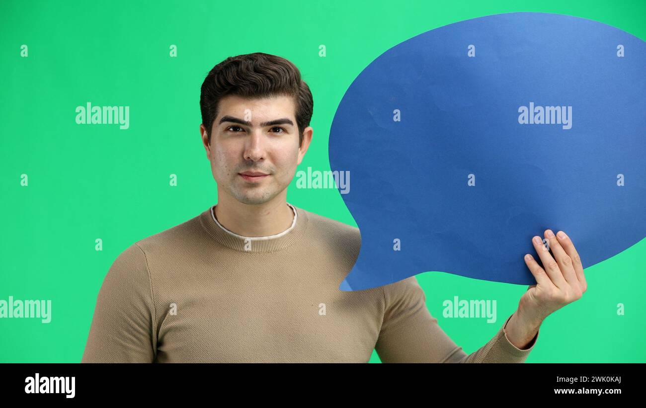 A man, close-up, on a green background, shows a blue comment sign Stock ...