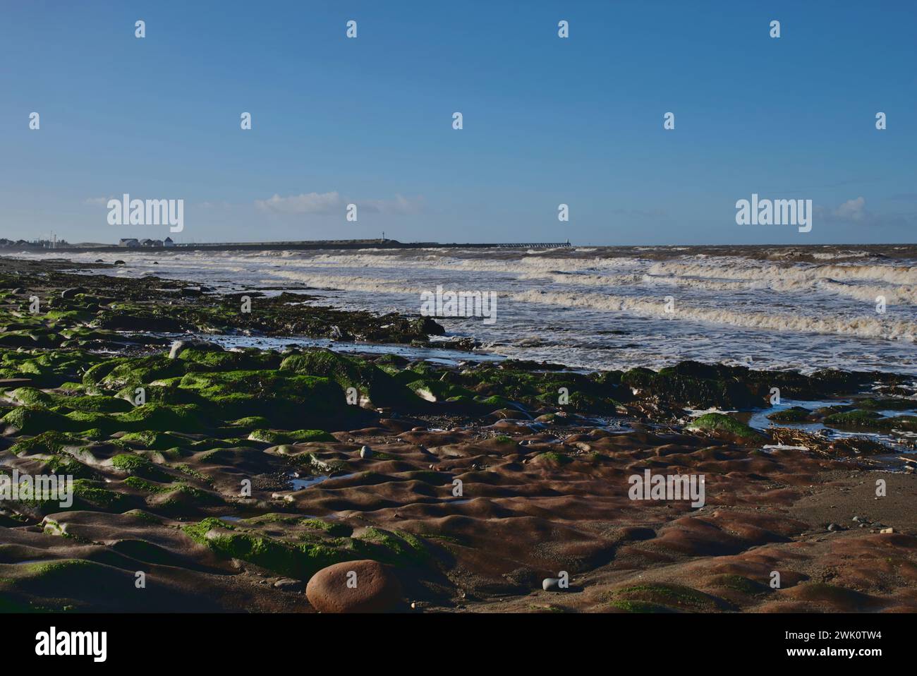 The harbour with Spring Tidal waves over the beach at Maryport, Cumbria ...