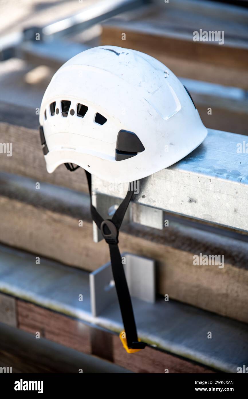 A white safety helmet placed on a metal carrier. The ventilation holes ...