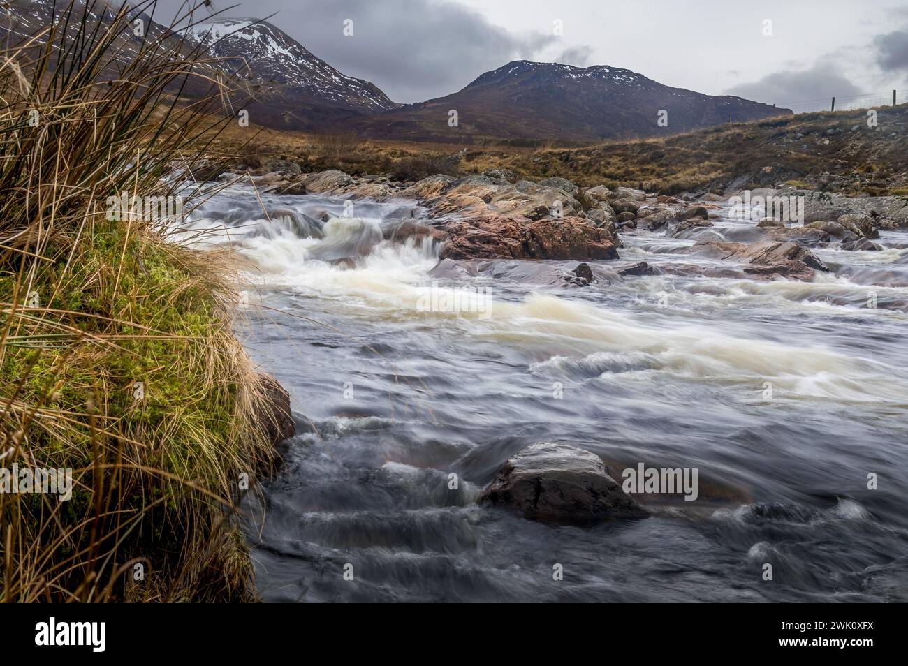 Fast flowing river over rocks with mountain background Stock Photo - Alamy