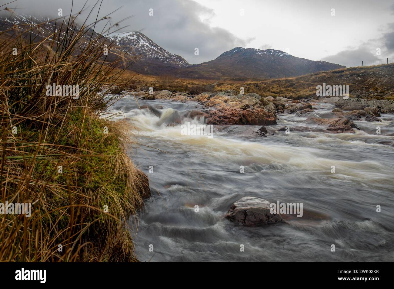 Fast flowing river over rocks with mountain background Stock Photo - Alamy