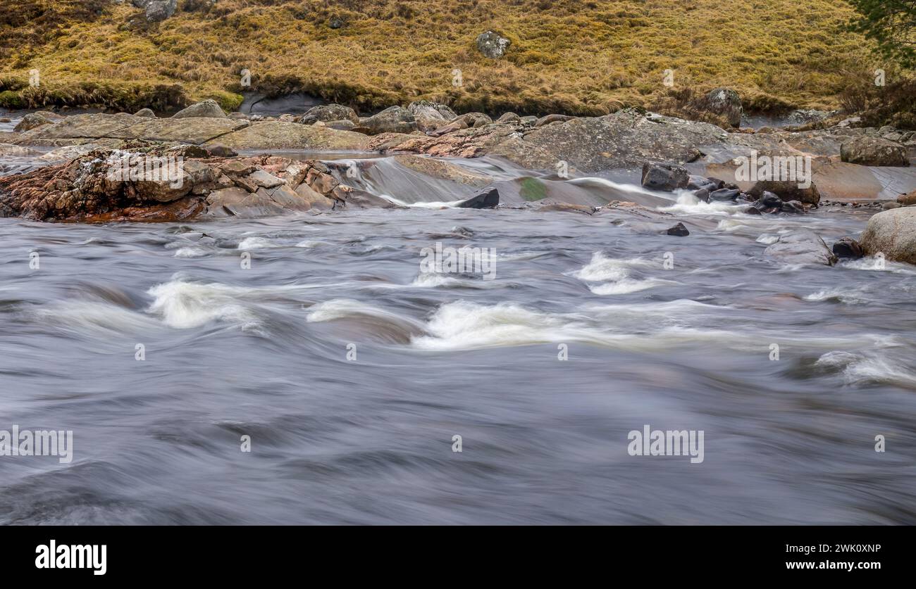 Fast flowing river over rocks with mountain background Stock Photo - Alamy