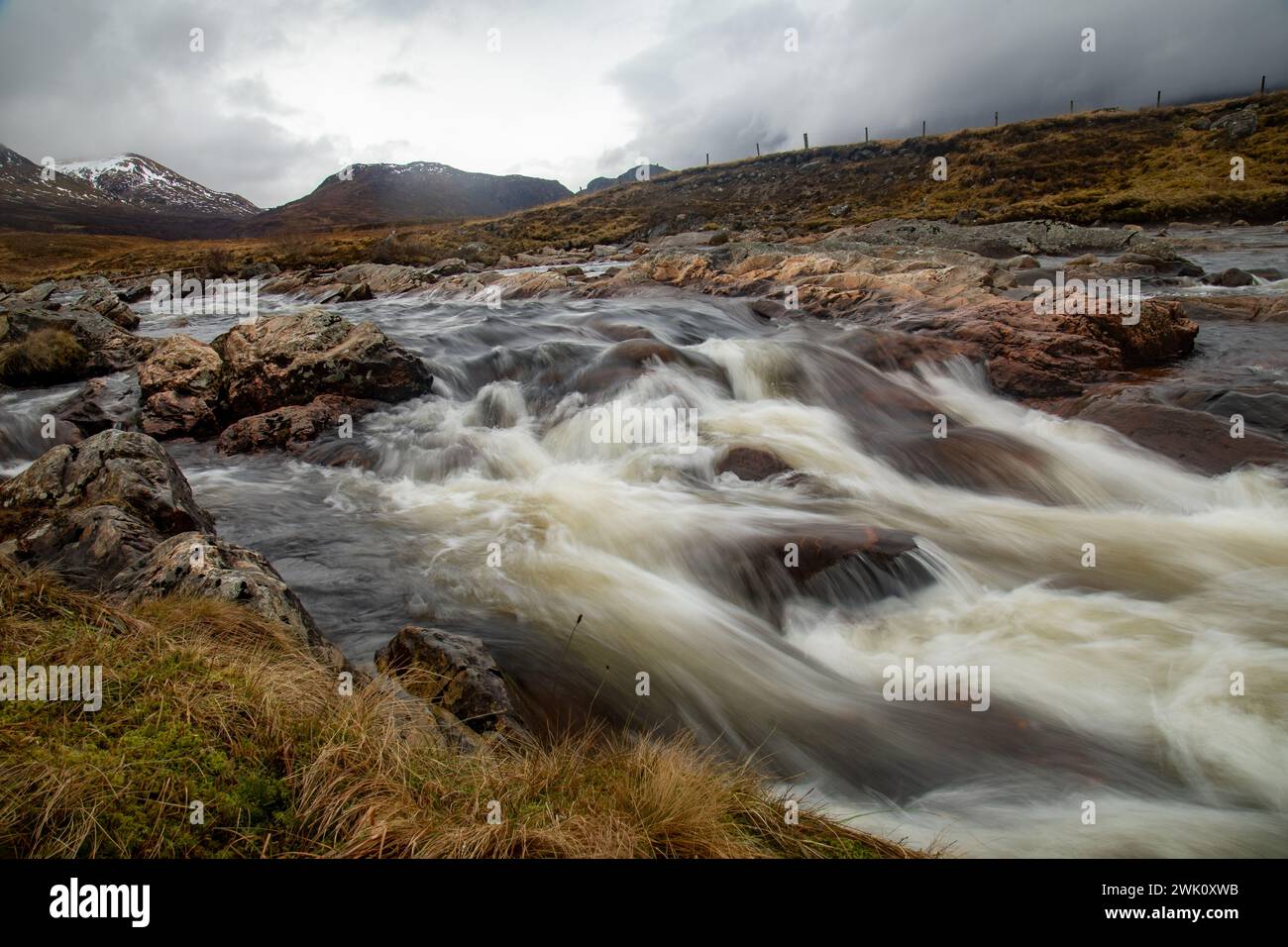 Fast flowing river over rocks with mountain background Stock Photo - Alamy