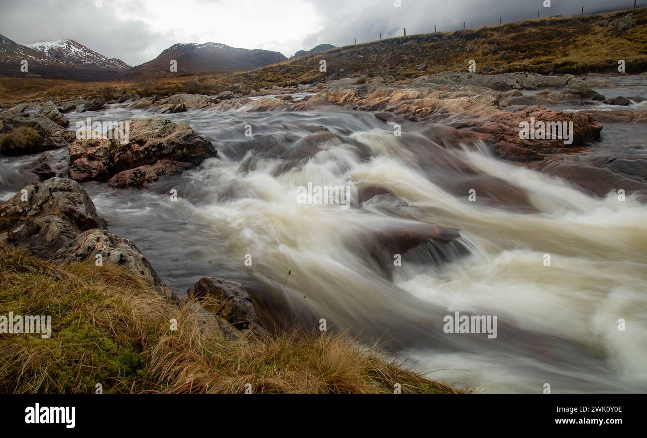 Fast flowing river over rocks with mountain background Stock Photo - Alamy