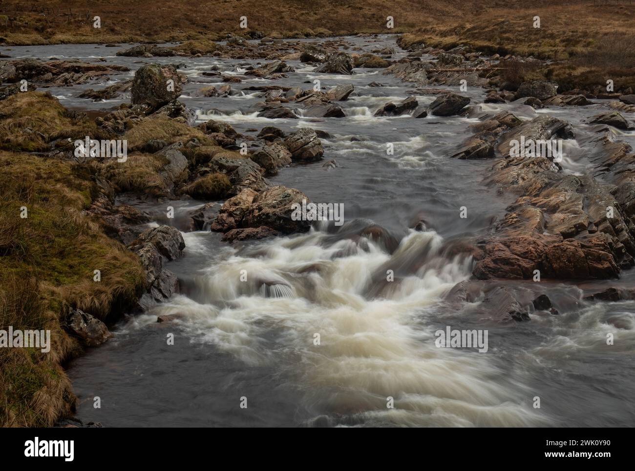 Fast flowing river over rocks with mountain background Stock Photo - Alamy