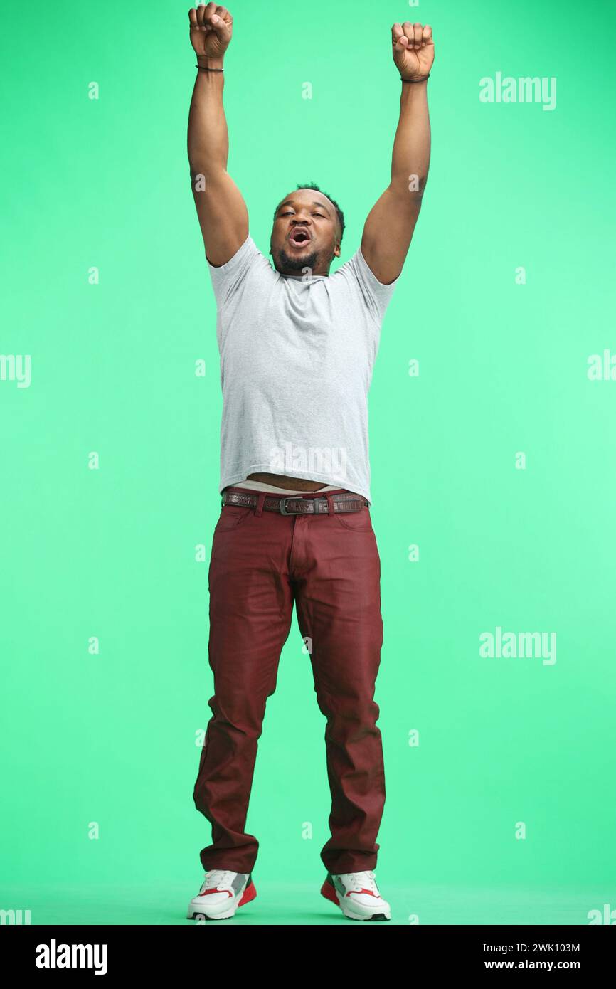 Man, full-length, on a green background, raised their hands up Stock ...