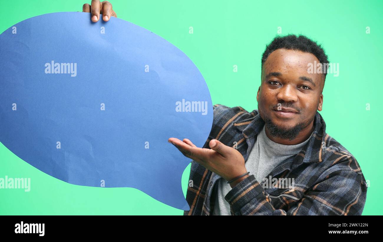 A man, close-up, on a green background, shows a blue comment sign Stock ...