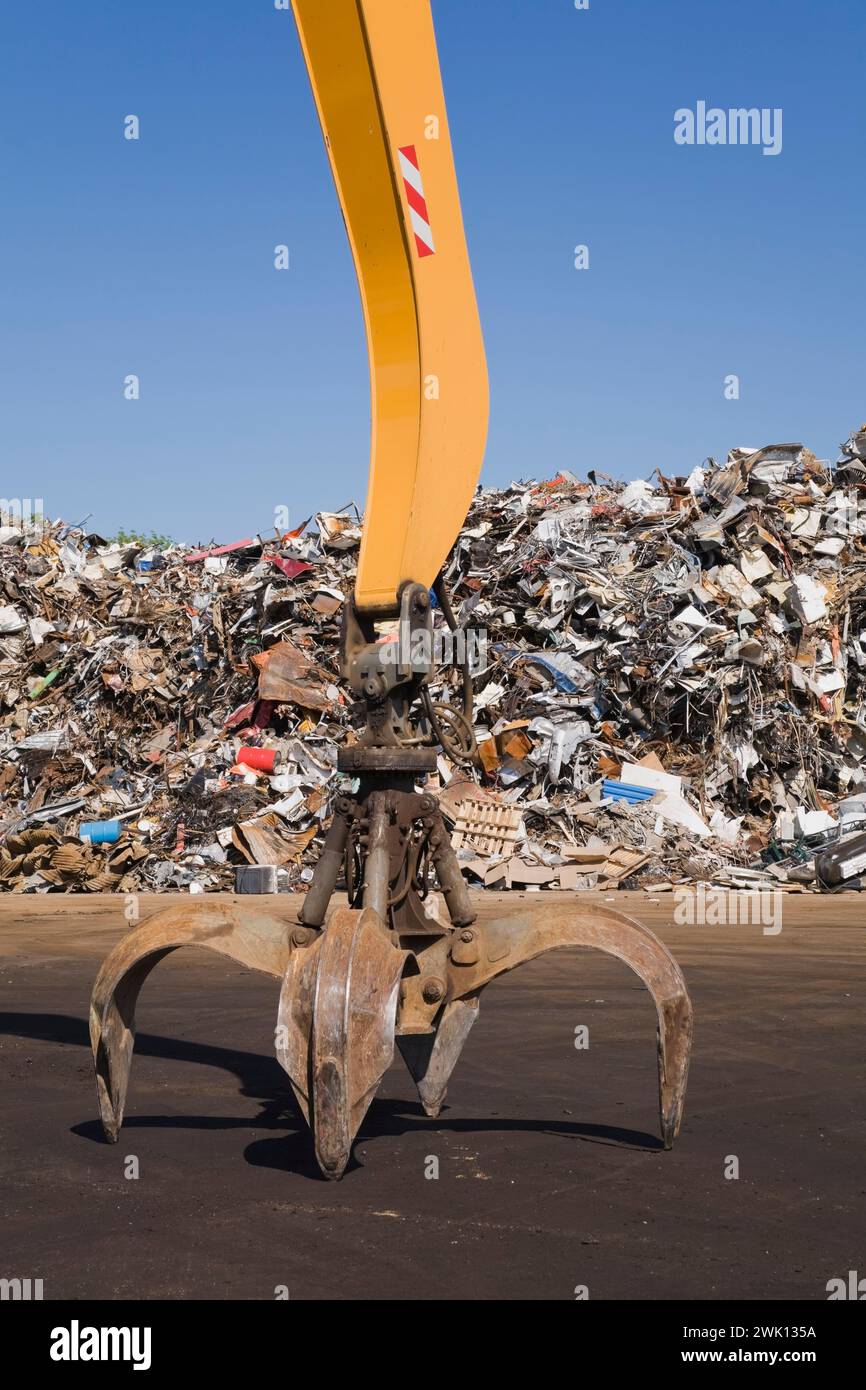 Grappling arm with claw clamp in front of pile of discarded metal ...
