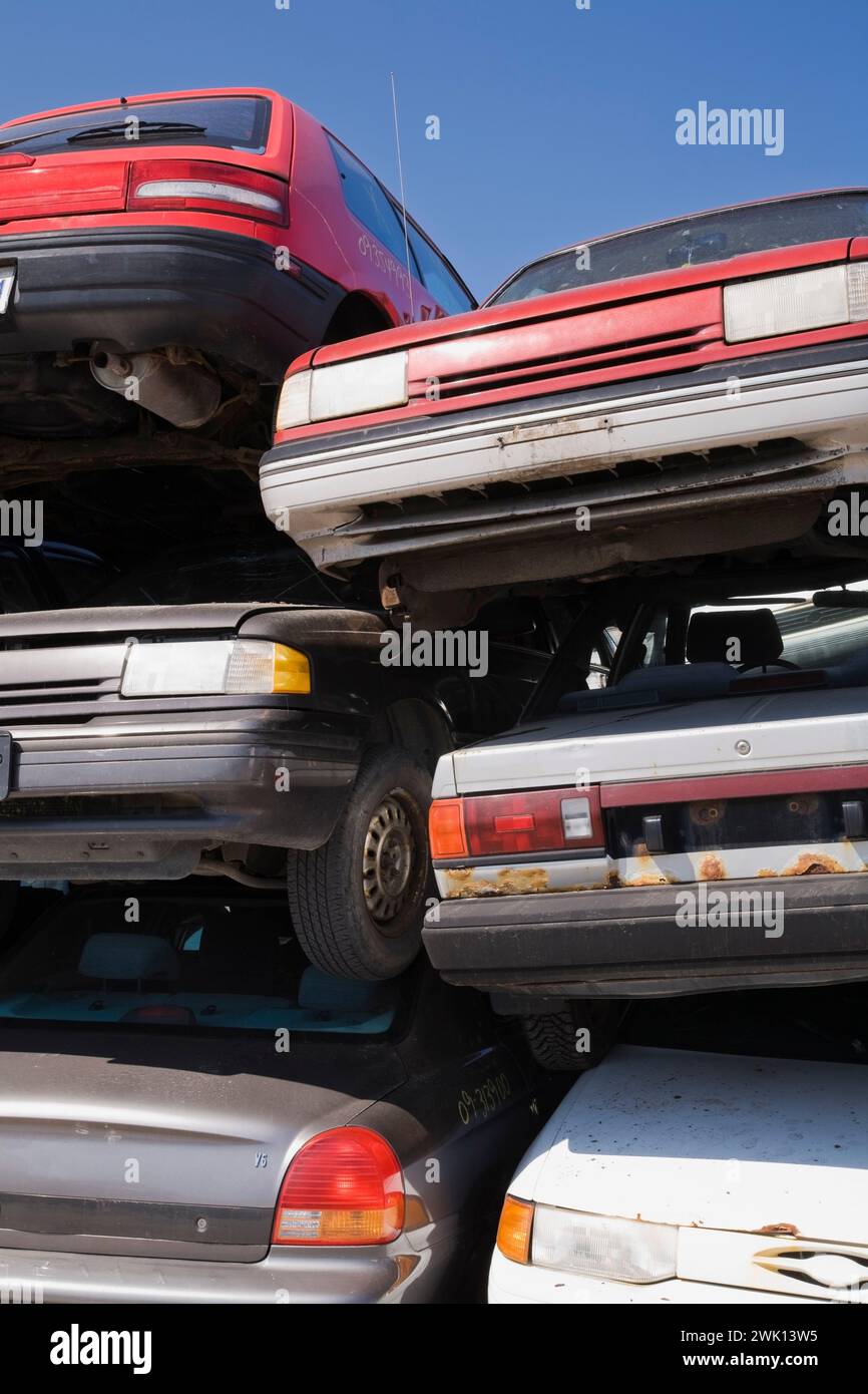Stacked and assorted automobiles at scrap metal recycling junkyard ...