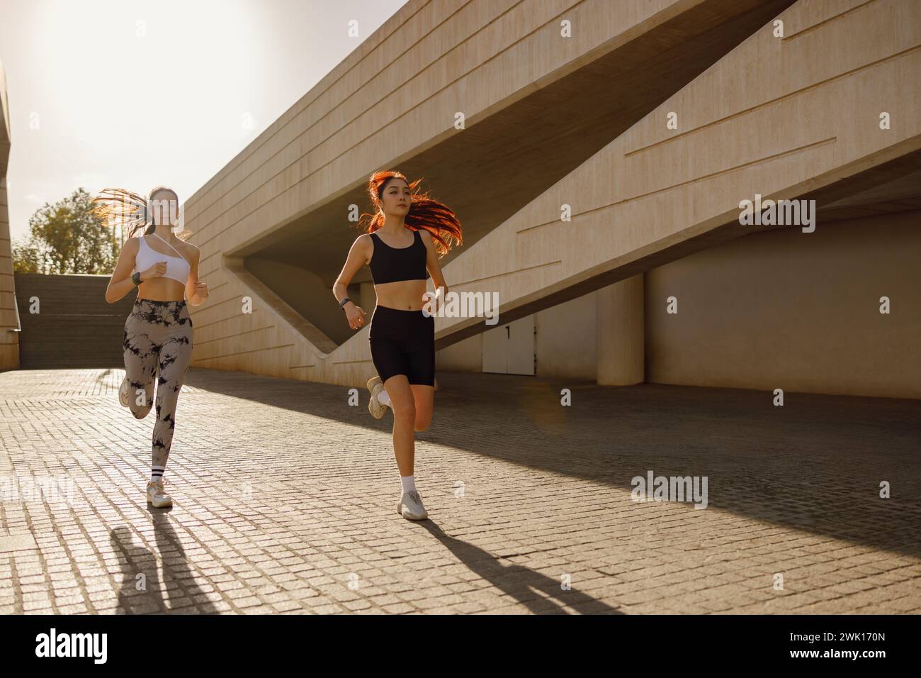Active women athlete running on sunny morning side by side on modern ...