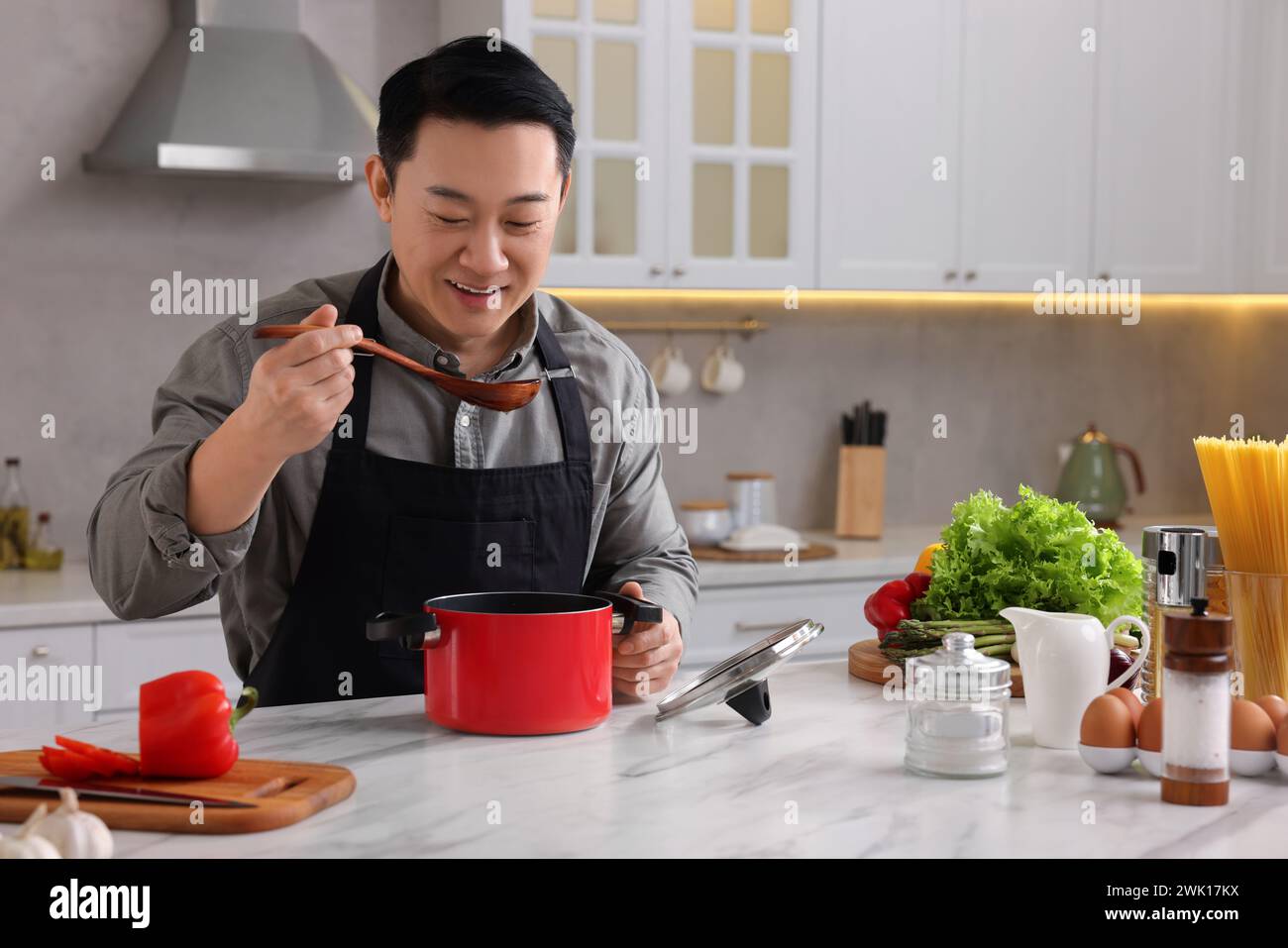 Cooking process. Man tasting dish at countertop in kitchen Stock Photo ...