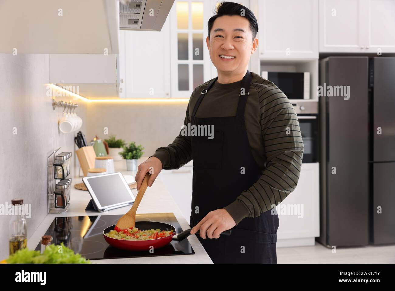 Happy man cooking dish on cooktop in kitchen Stock Photo - Alamy