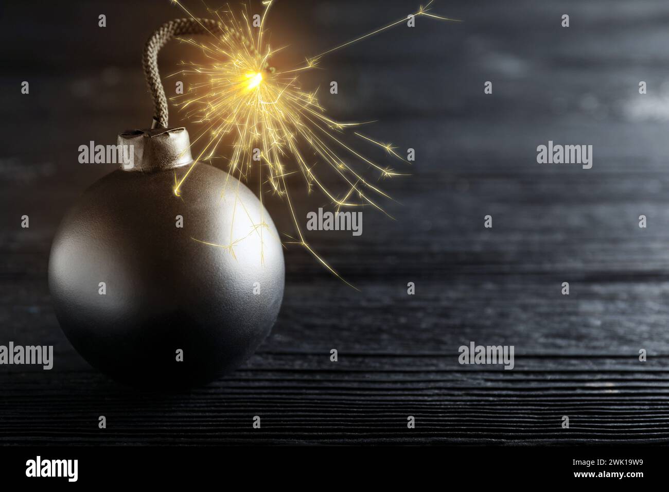 Old fashioned bomb with lit fuse on black wooden table, space for text ...