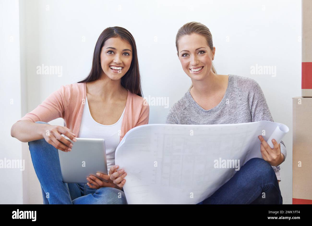 Women, blueprint and happy on floor at startup with tablet, idea or ...