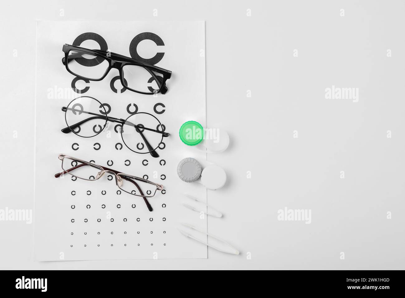 Vision test chart, glasses, lenses and tweezers on white background ...
