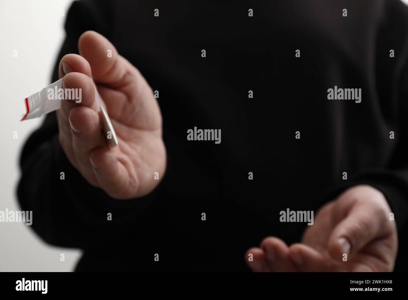 Drug addiction. Man with plastic bag of cocaine on light background ...