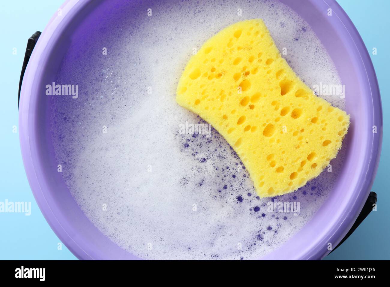 Bucket with foam and sponge on light blue background, top view Stock ...
