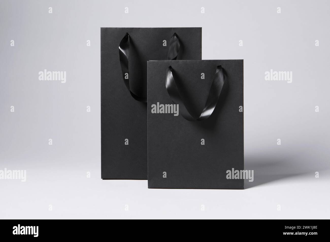 Black paper bags on light grey background Stock Photo - Alamy