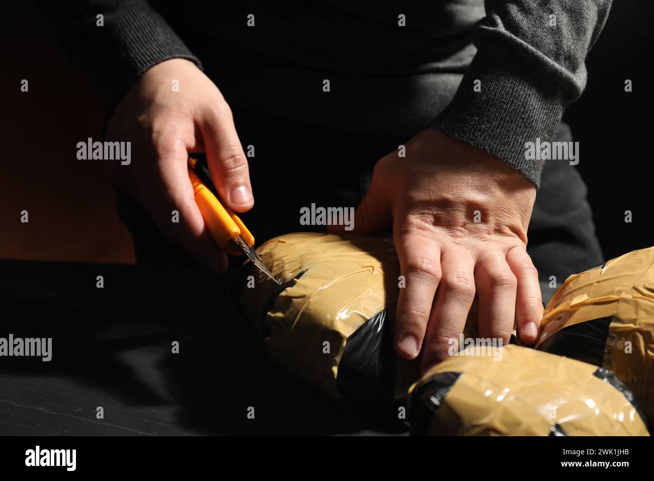 Smuggling and drug trafficking. Man opening package of narcotics with ...