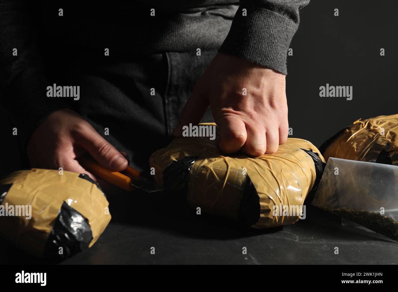 Smuggling and drug trafficking. Man opening package of narcotics with ...