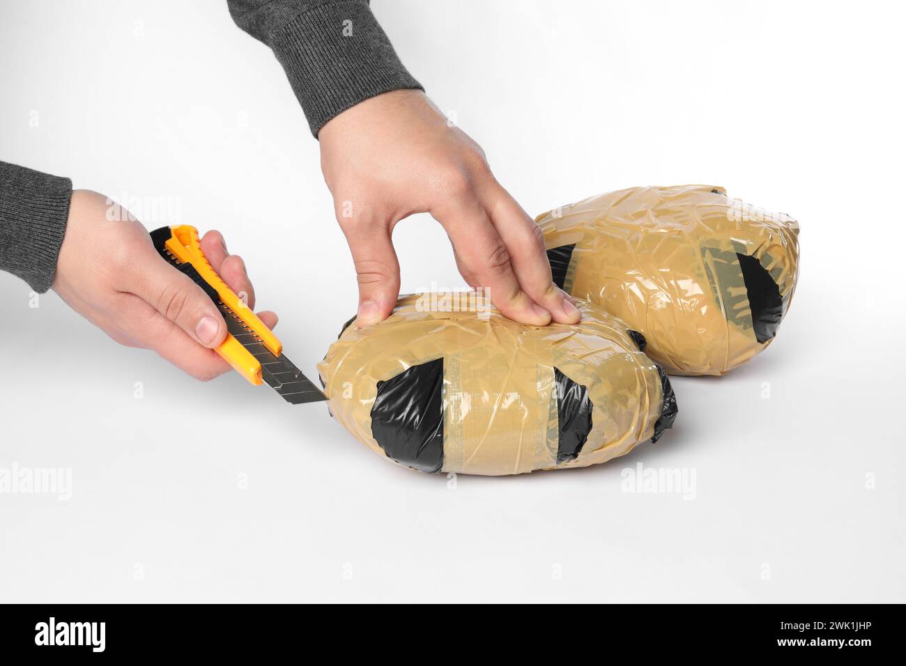 Smuggling and drug trafficking. Man opening package of narcotics with ...