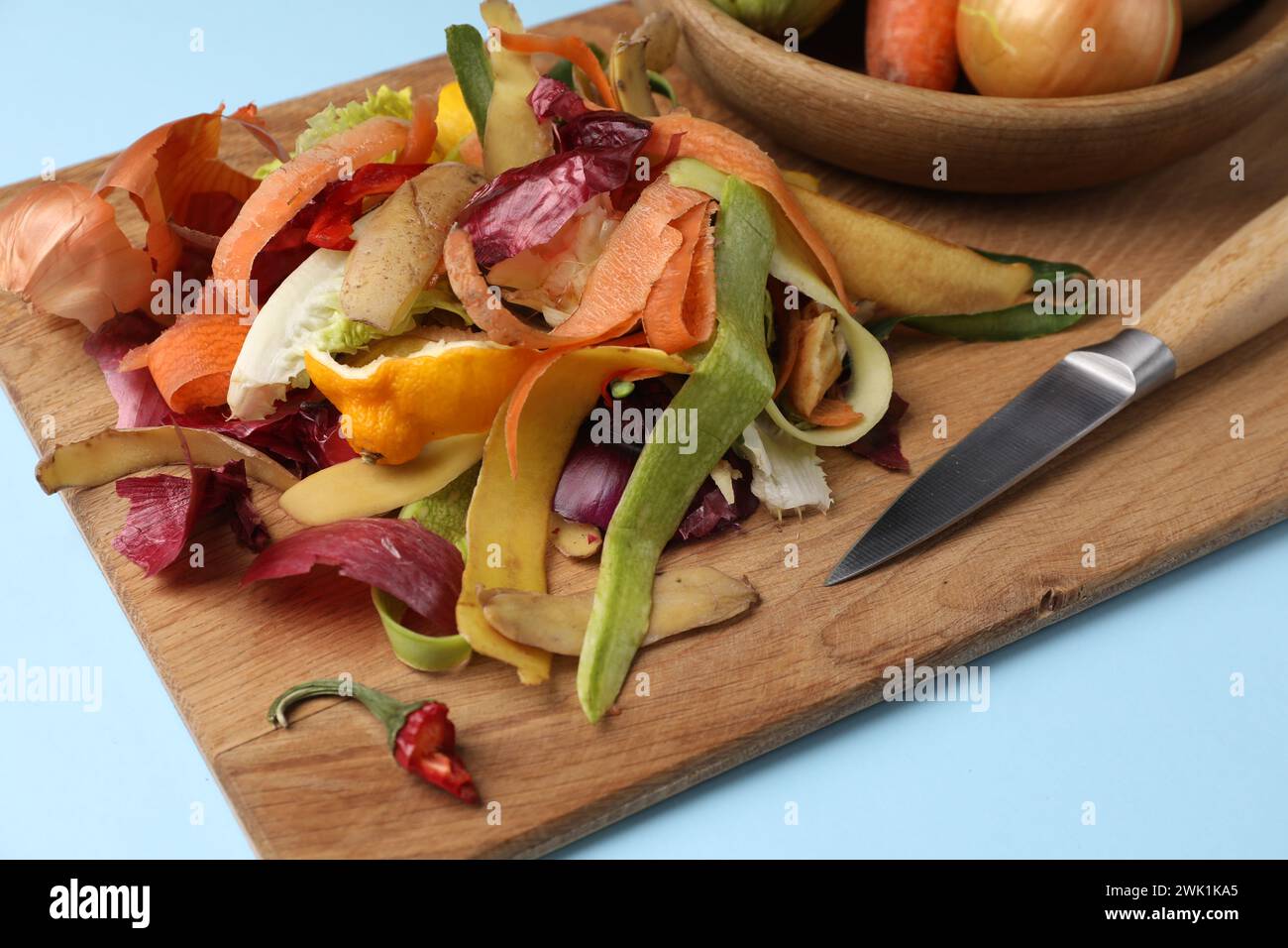 Different fresh vegetables with peels and knife on light blue ...
